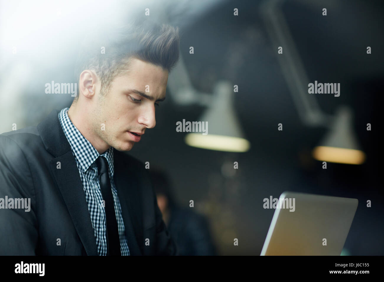Side view portrait of handsome young businessman using laptop in office, focused on work Stock ...