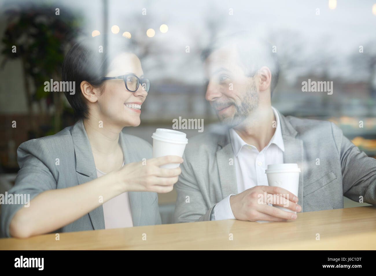 Two happy colleagues with hot drinks interacting at break Stock Photo ...