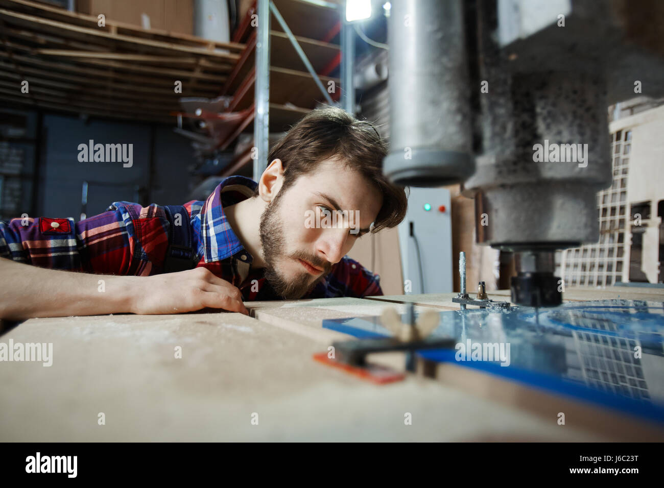 Portrait of handsome young engineer operating glass cutting machine ...