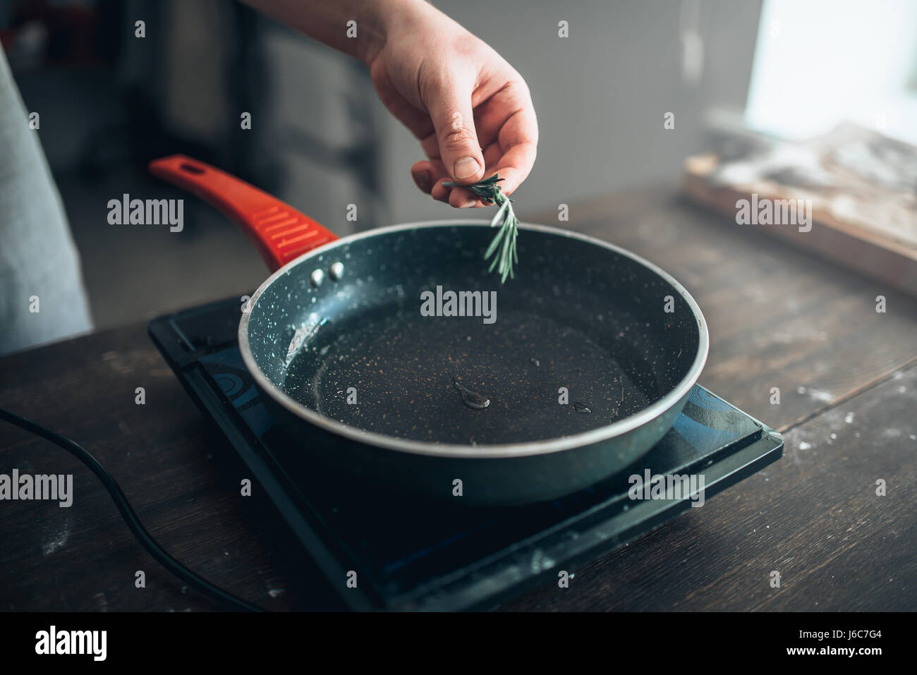 Male chef hands puts rosemary in a frying pan. Food cooking. Fish and ...