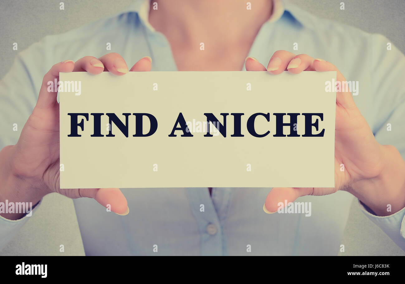 Closeup businesswoman hands holding white card sign with Find a Niche ...