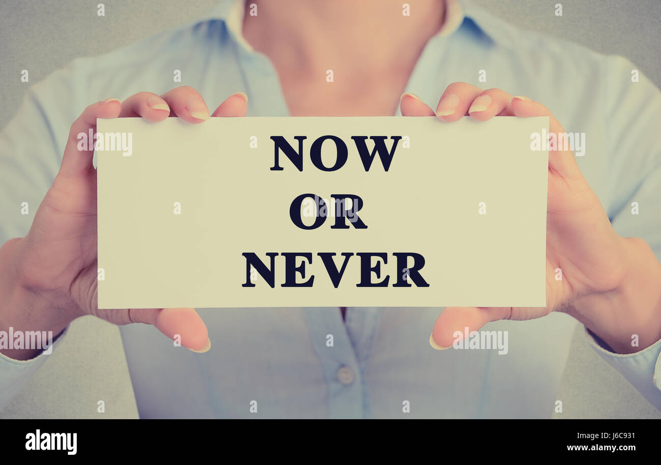Businesswoman hands holding white card sign with now or never text ...
