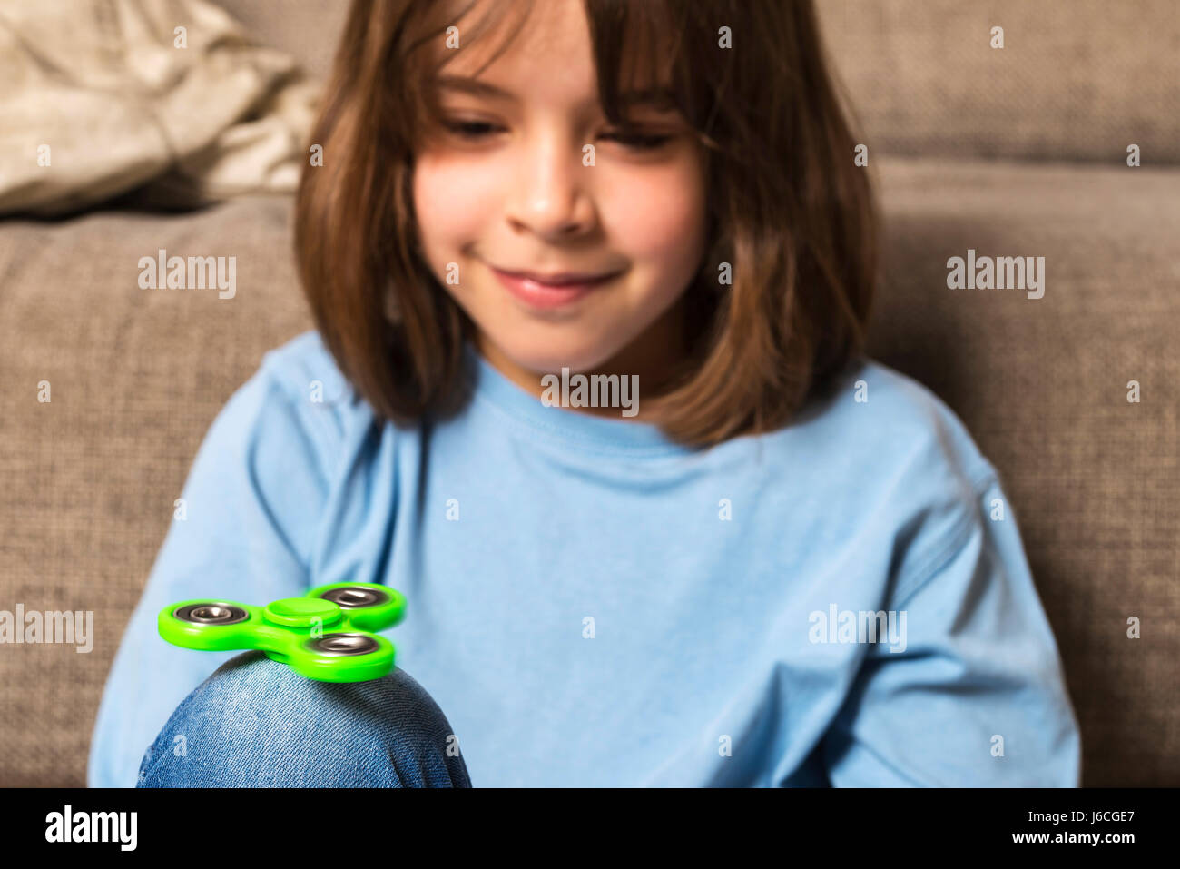 Little girl playing with green fidget spinner toy to relieve stress at ...