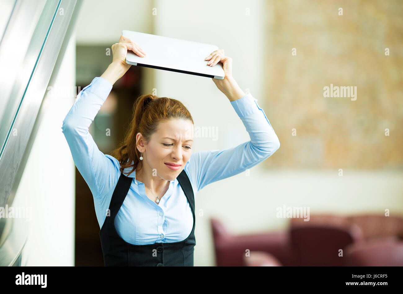 Portrait stressed, angry businesswoman throwing her tablet computer ...