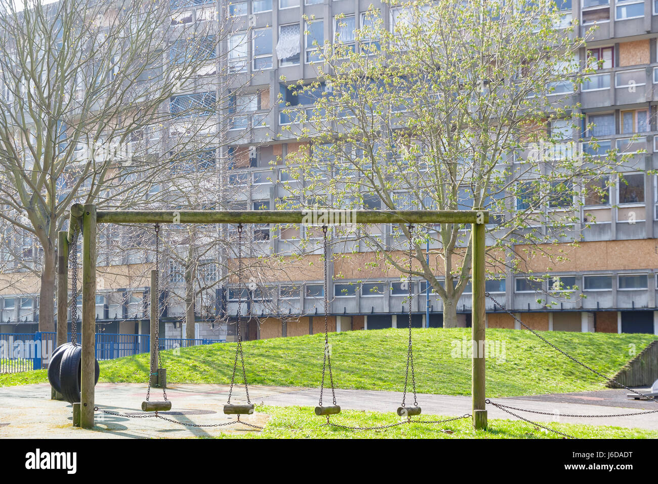 Old wooden playground and swings with a dilapidated council flat ...