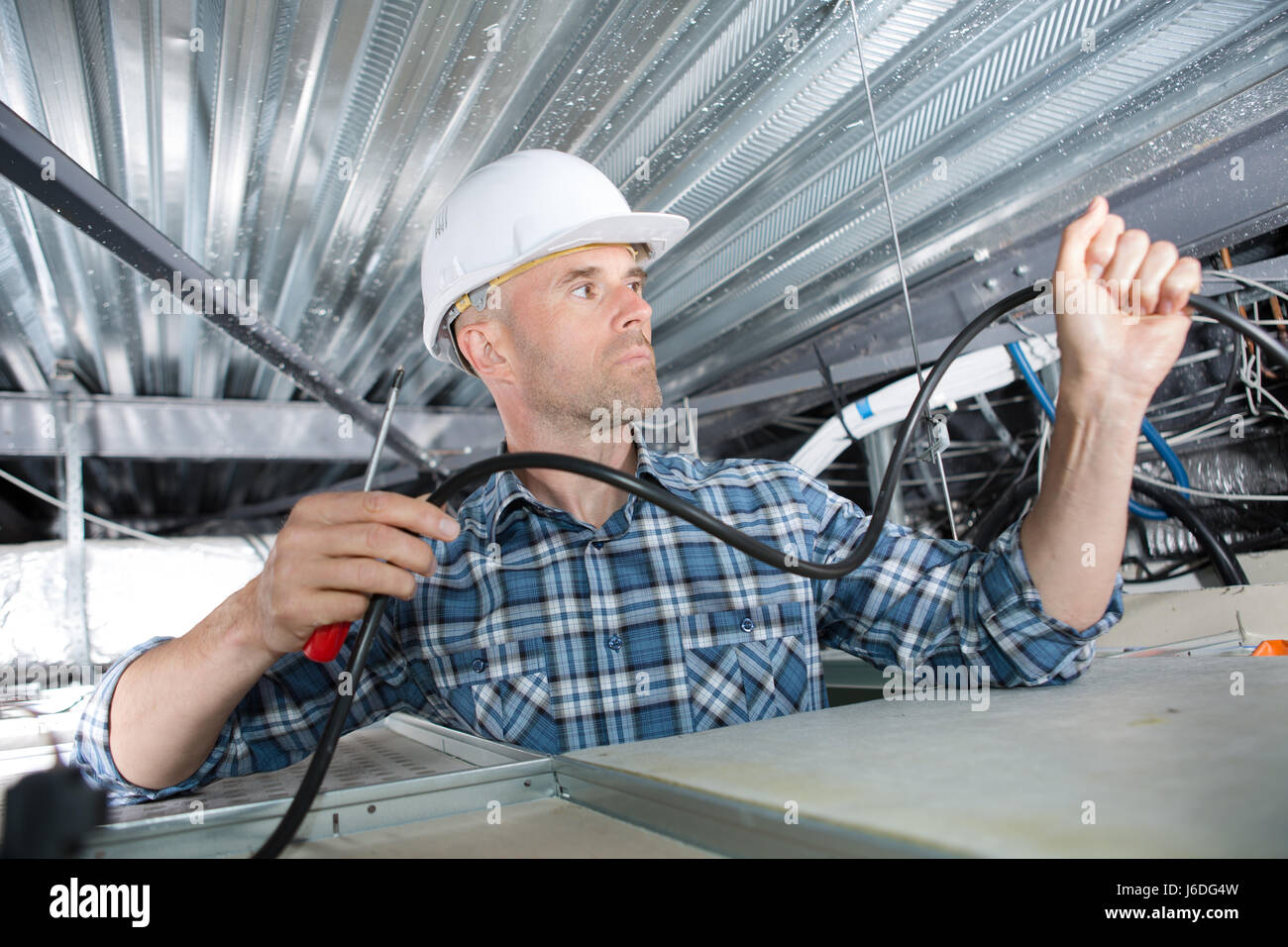 Electrician installing cables in roof Stock Photo - Alamy
