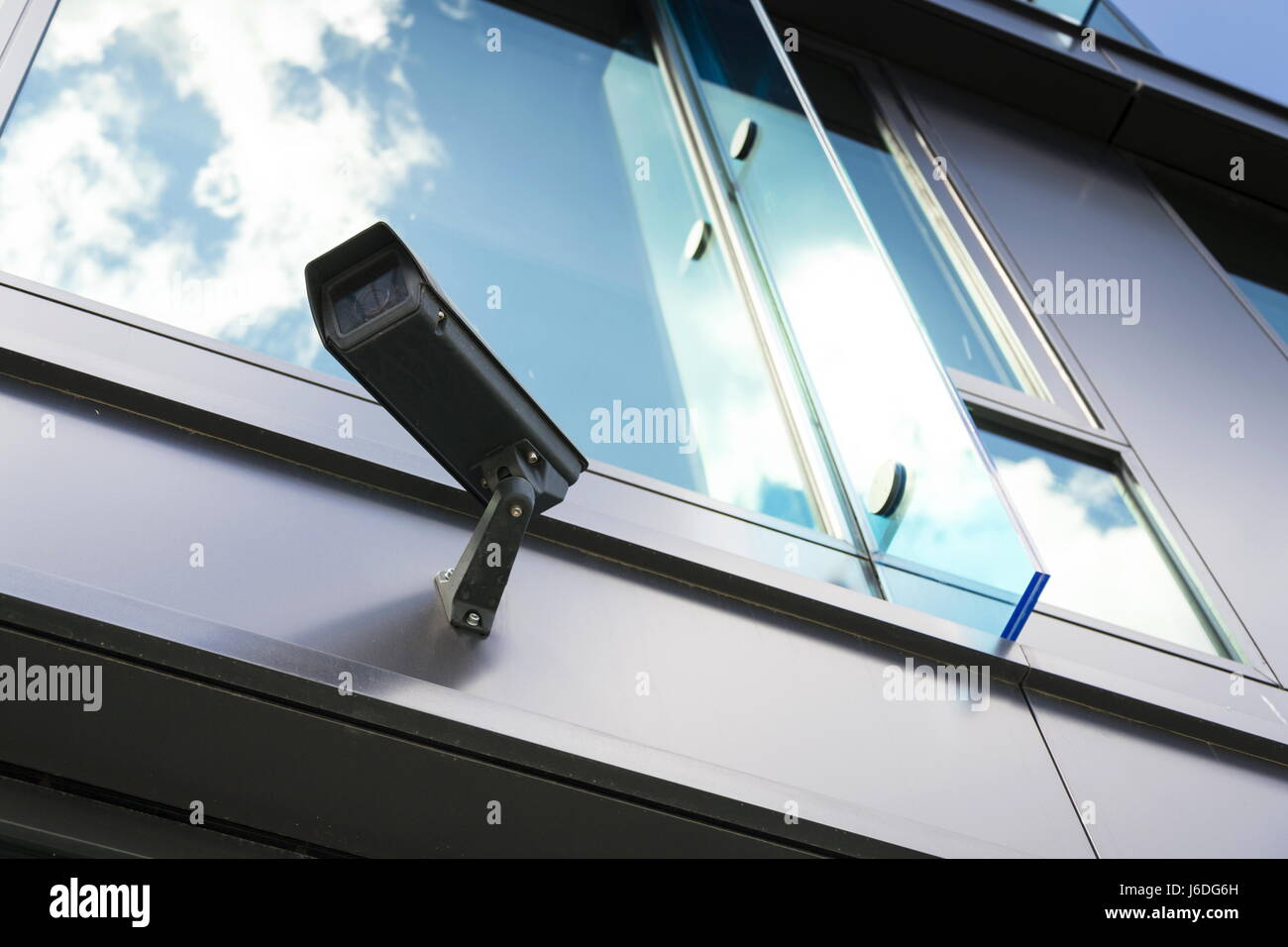 Grey security camera with window reflecting blue sky clouds Stock Photo ...