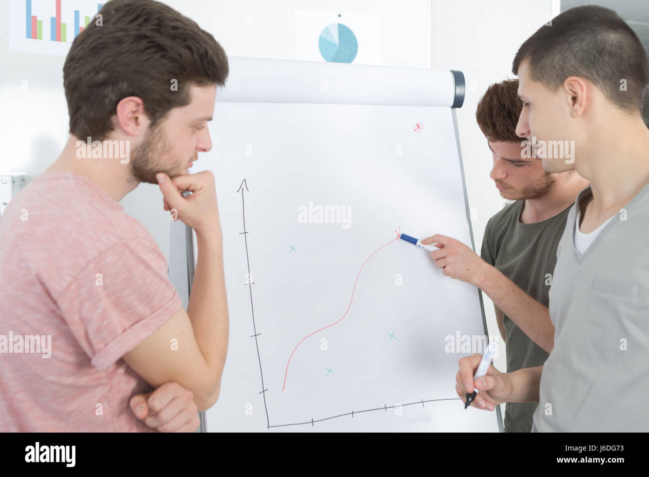 Young men tracing graph on flip chart Stock Photo - Alamy