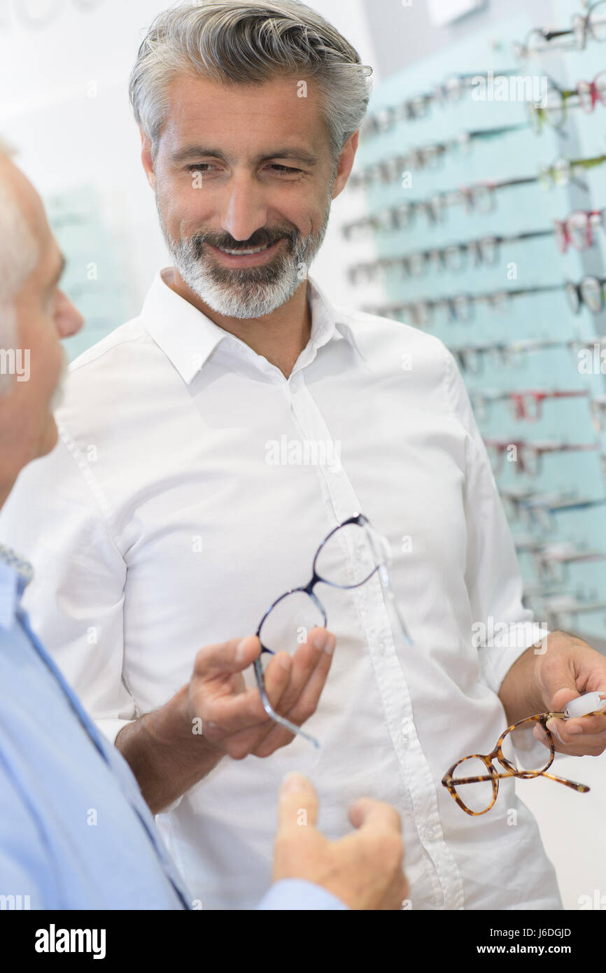 Optician passing frames to customer Stock Photo - Alamy