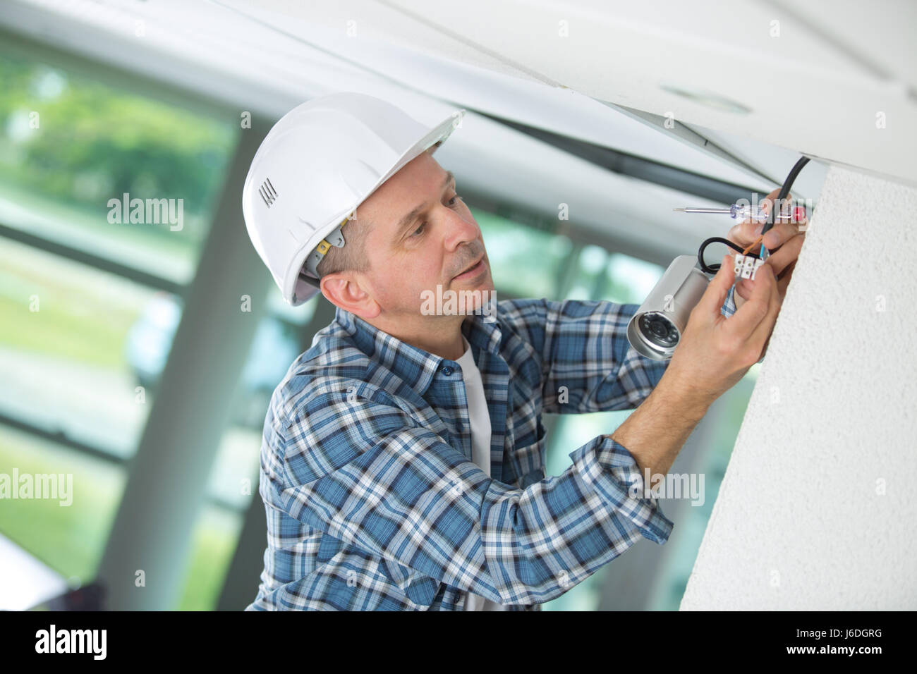 Contractor fitting interior cctv camera Stock Photo - Alamy