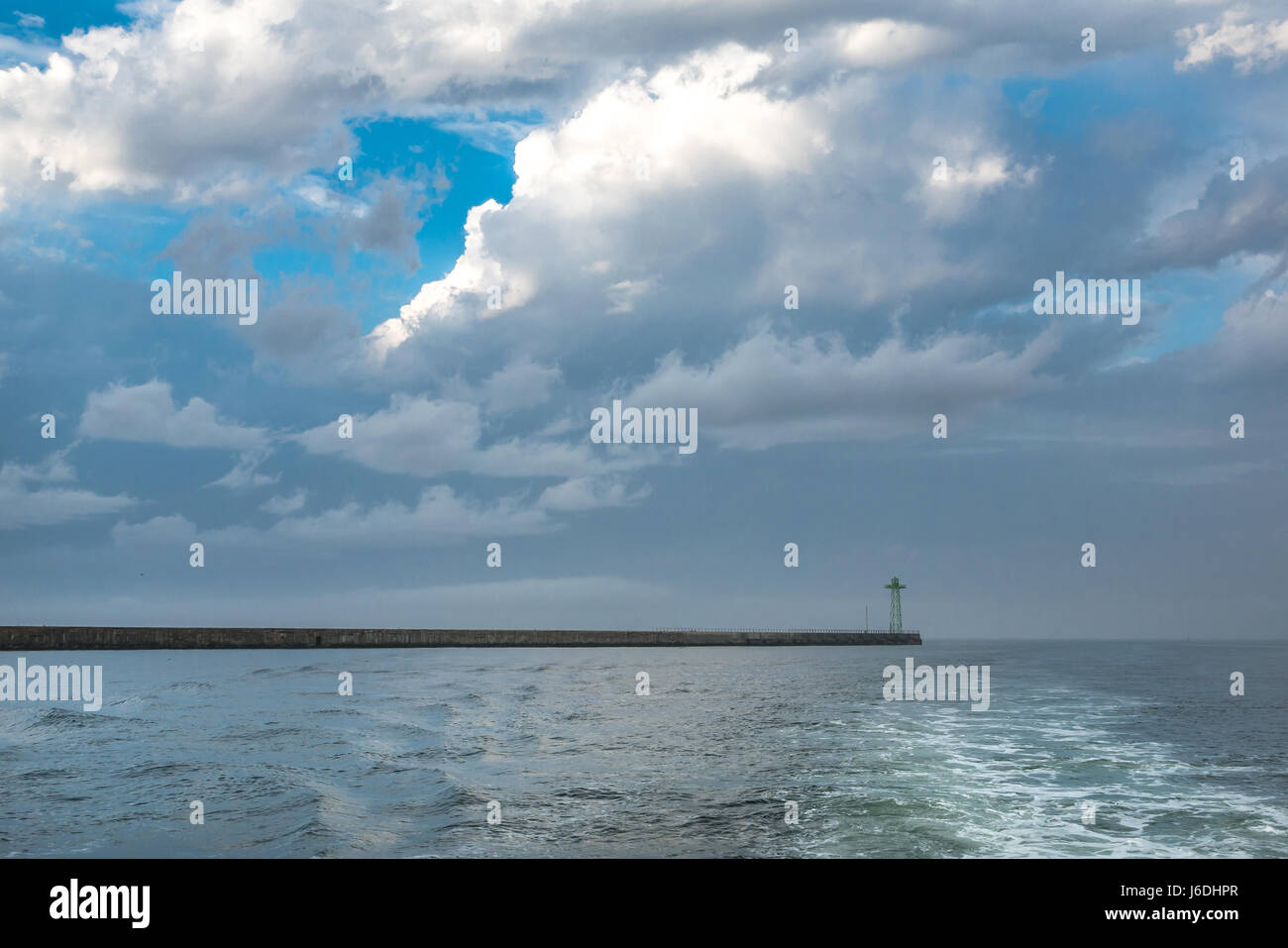 View across harbour with long pier with navigation marker and jetty ...