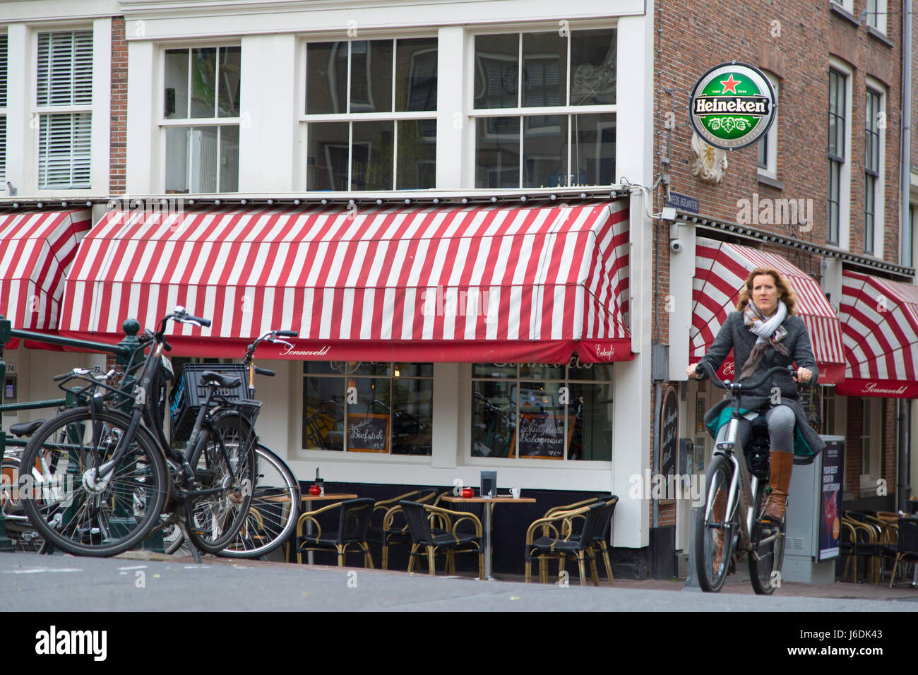 Woman cycling past cafe on Egelartiersgracht canal, Amsterdam ...