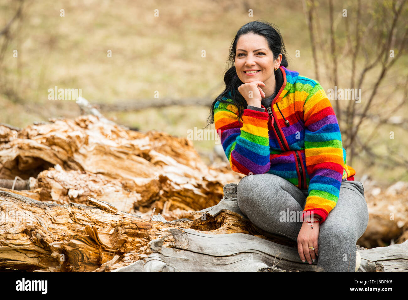 Cheerful woman sitting on a bark tree in nature and holding hand to ...