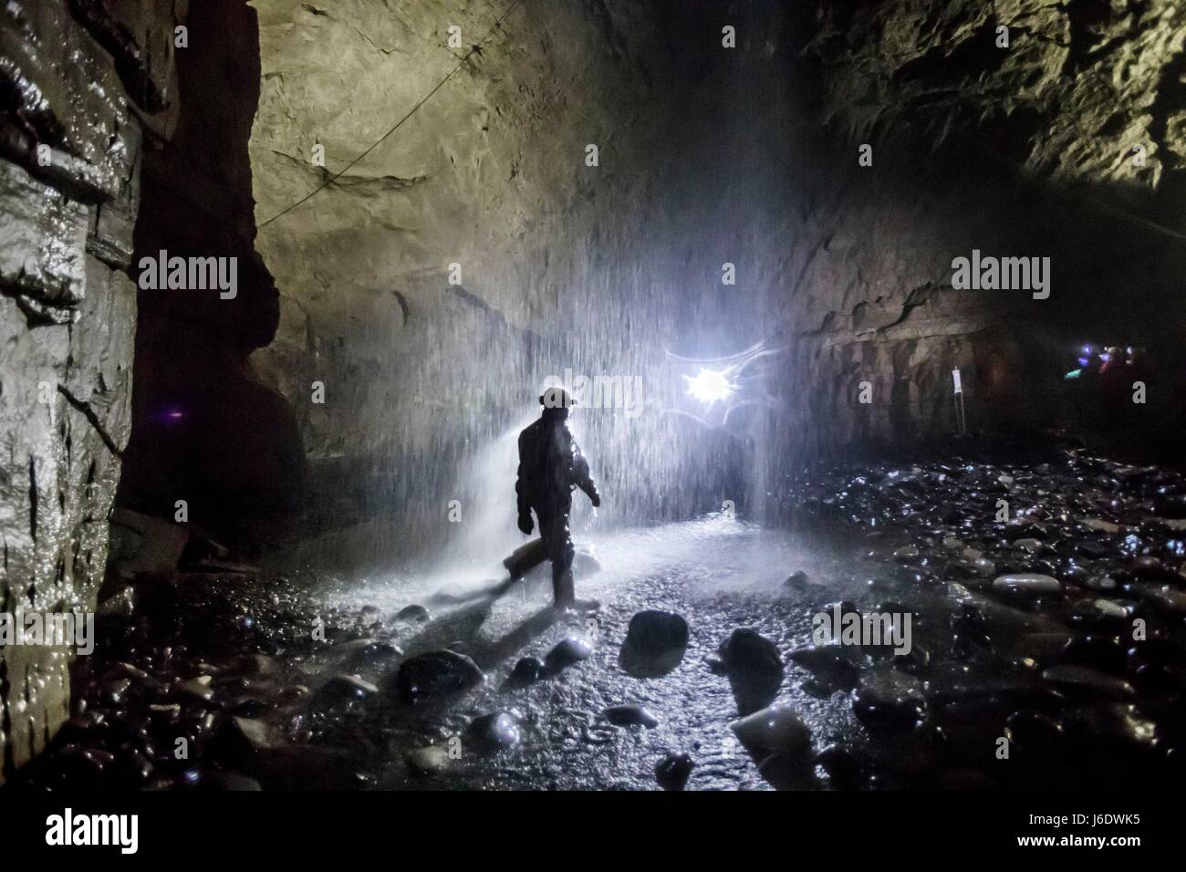 A potholer walks through Fell Beck stream as they explore Gaping Gill ...