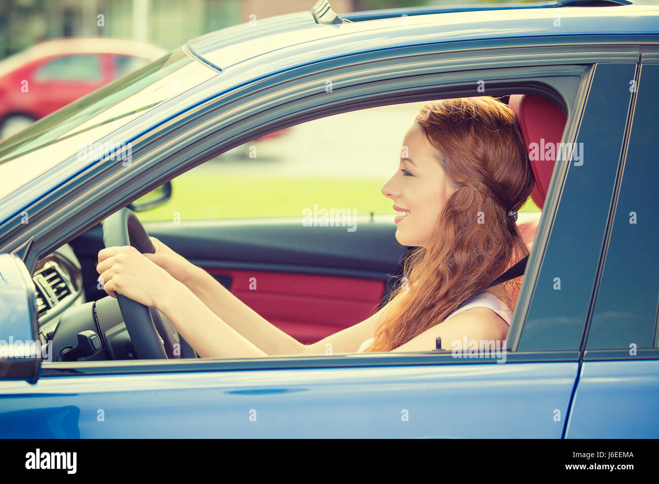 Happy beautiful young woman driving her new blue car Stock Photo - Alamy