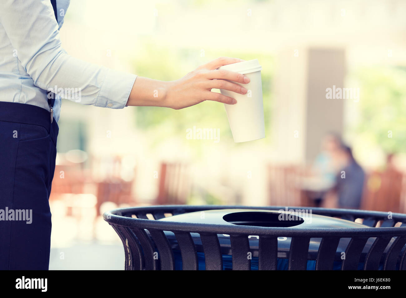 Closeup cropped image woman's hand throwing empty paper coffee cup in ...