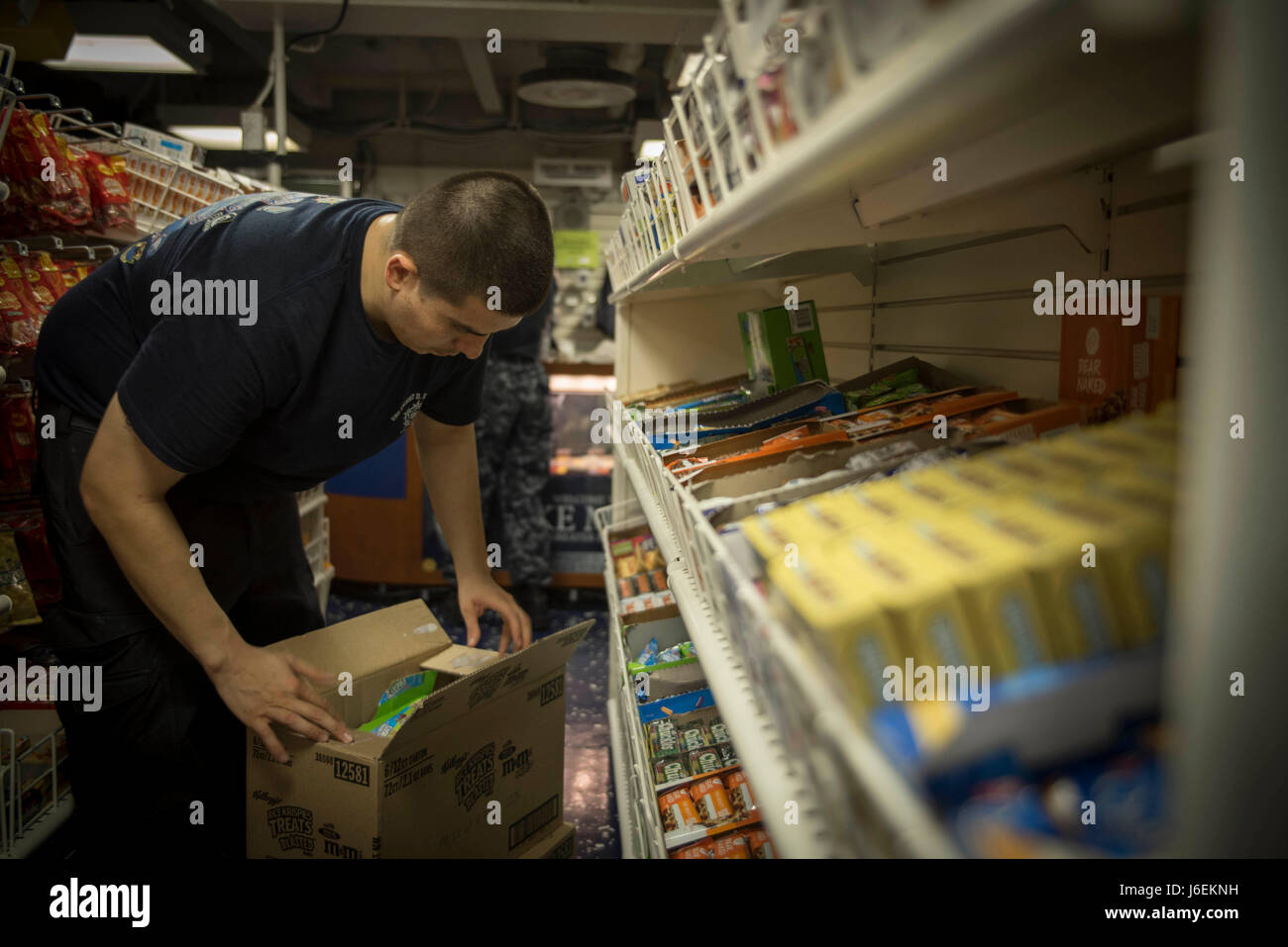 A sailor stocks shelves in the ship store aboard the aircraft carrier ...