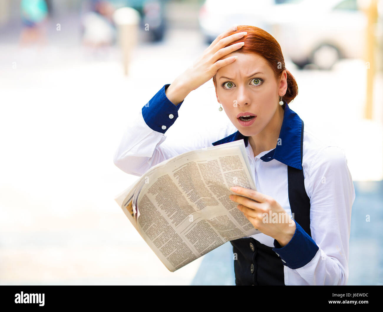 Astonished businesswoman reading newspaper outside her office ...