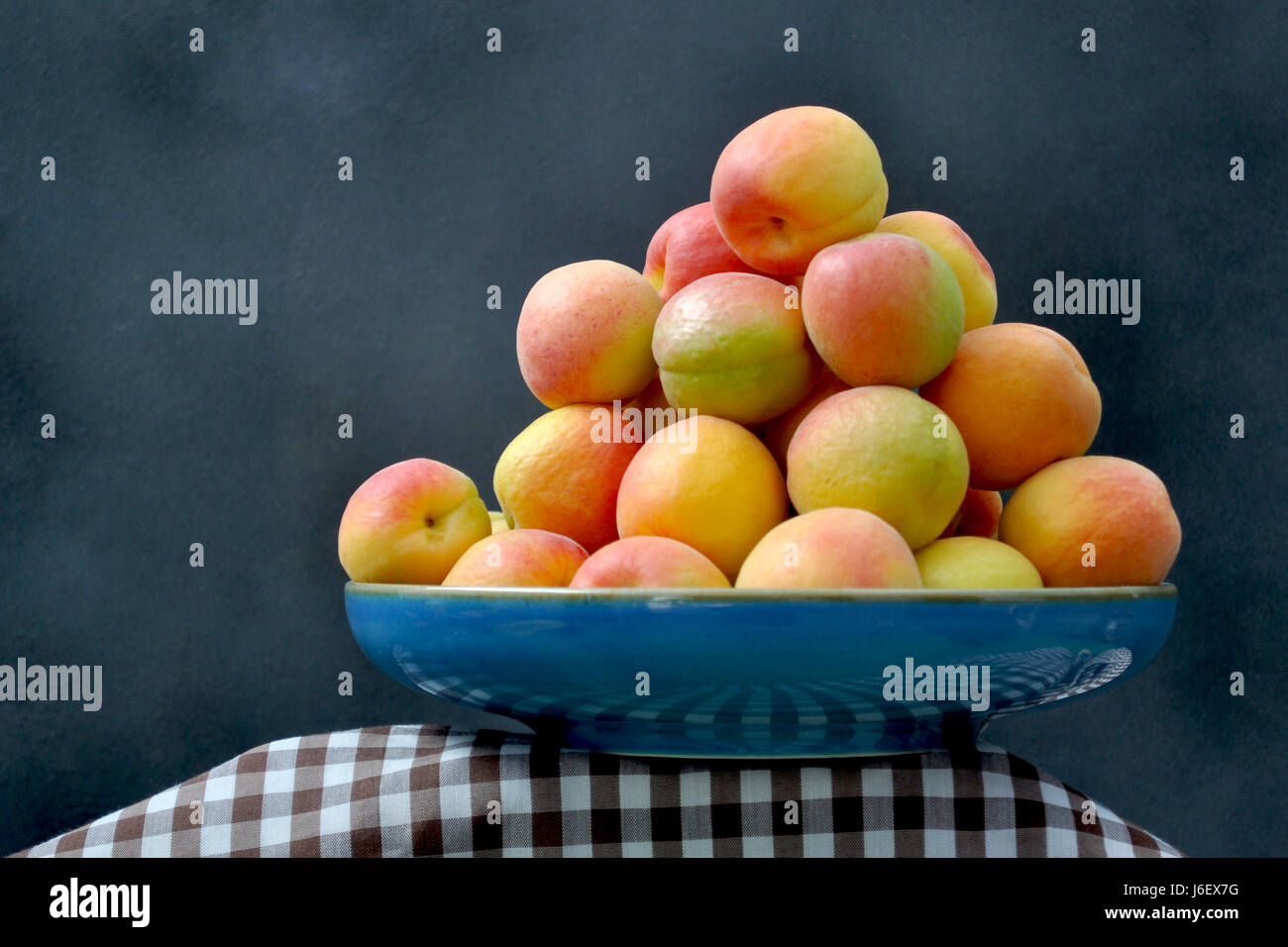 blue dish with red and yellow apricots on a tablecloth brown Stock ...