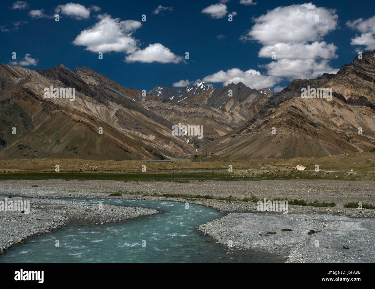 The turquoise stream of the river flows through the high mountains of ...