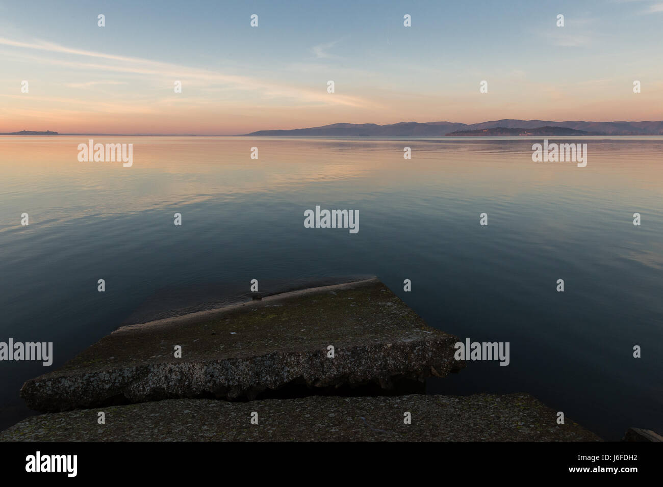 A semi-submerged concrete pier on a lake, at dusk, with beautiful soft ...