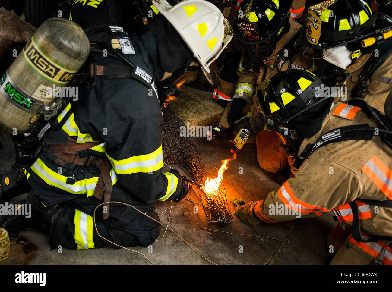Instructor, Jason Krusen, lights wire on fire as firefighters use a ...