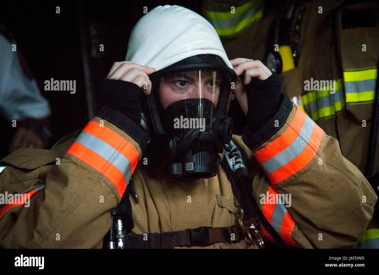 A firefighter puts on his protective equipment prior to a live burn ...