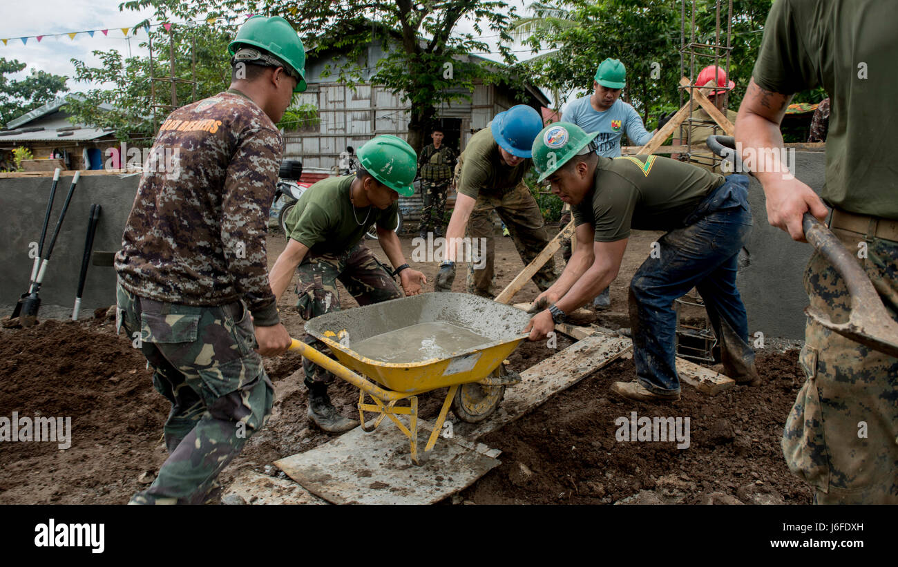 Philippine and U.S. service members pour concrete for a gate foundation ...