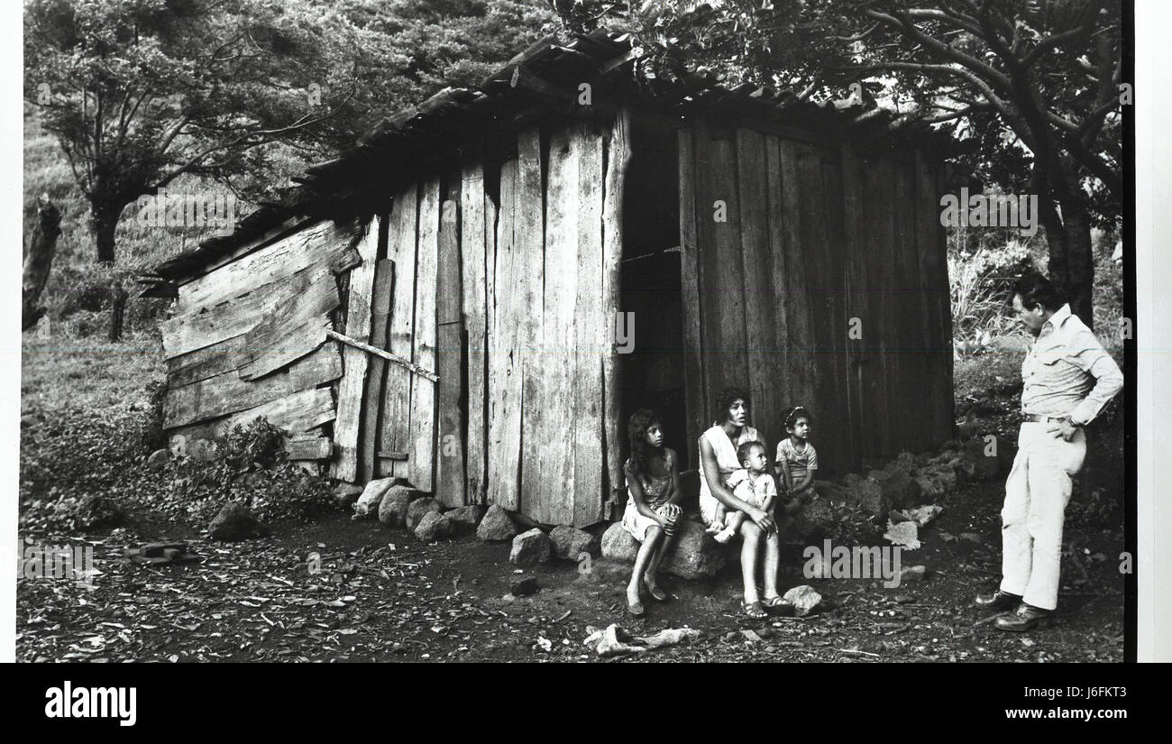 A MAN IS TALKING TO A WOMEN AND HER CHILDREN ON THE SIDE OF A SHACK ...