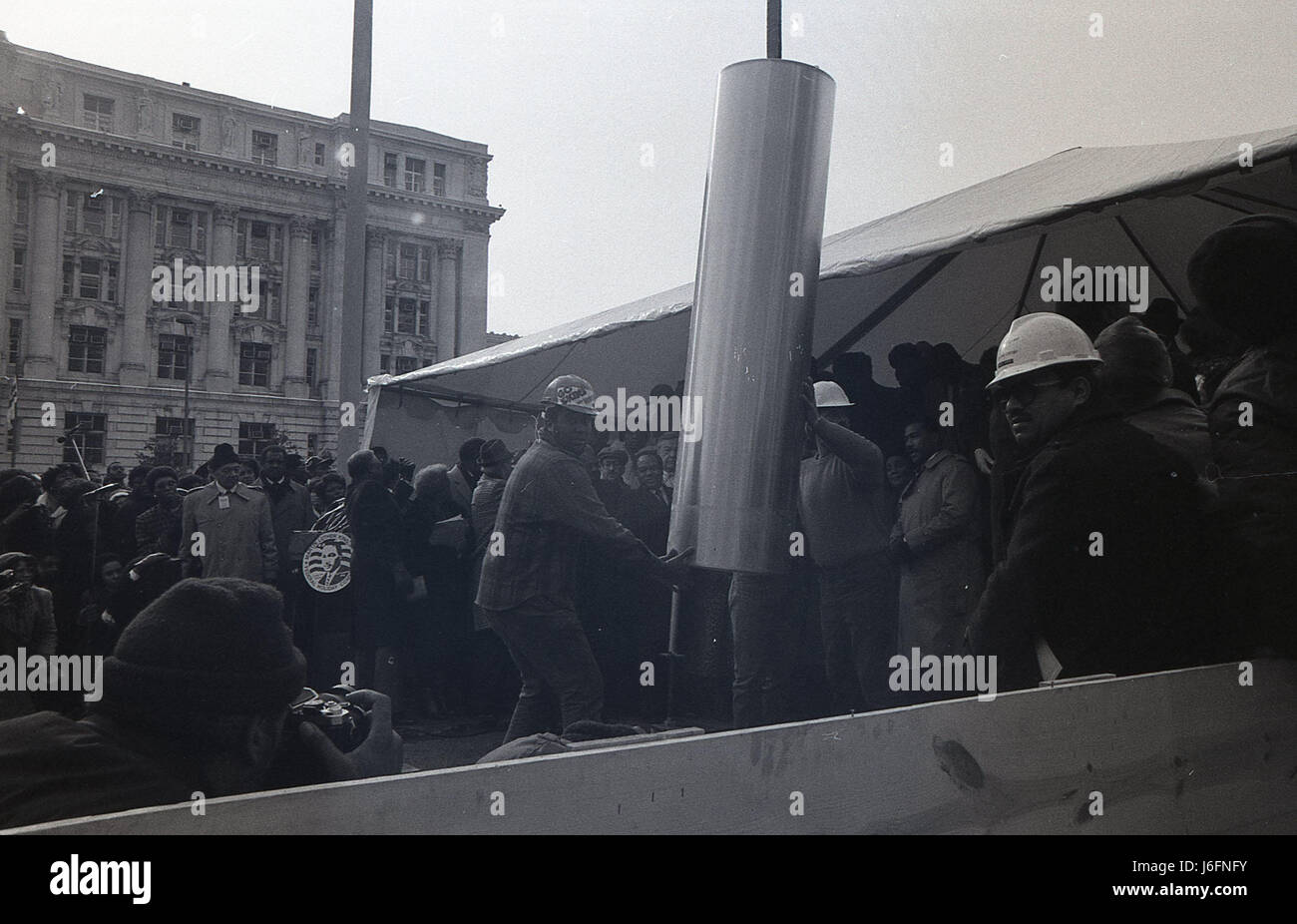 crowd surrounding man holding a big object Stock Photo - Alamy