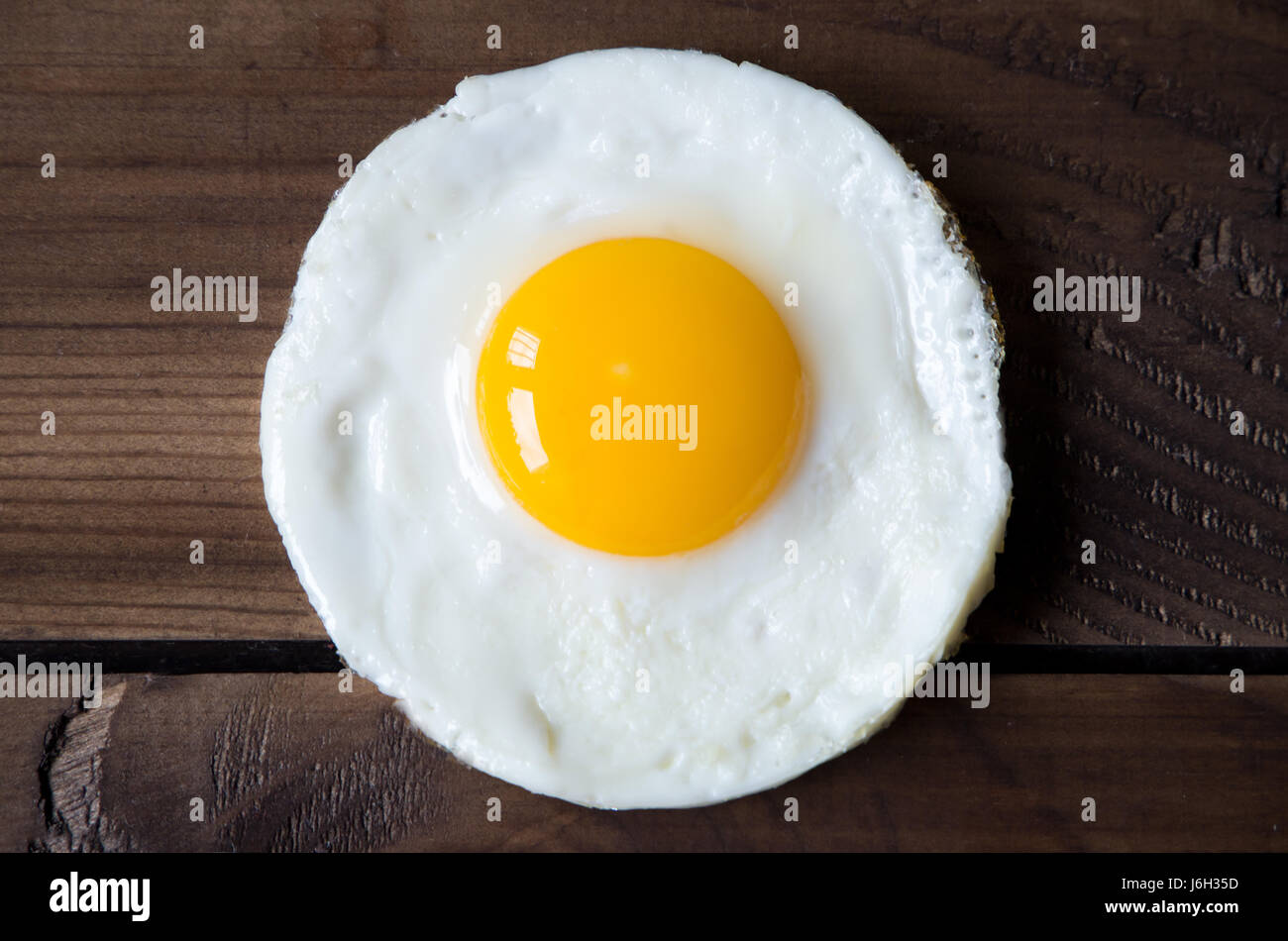 close up of round shaped fried egg for healthy breakfast on dark wooden ...