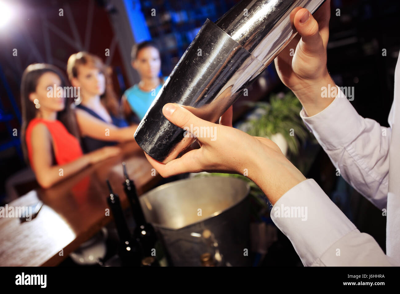 Waiter shaking a cocktail, young women on the background Stock Photo ...