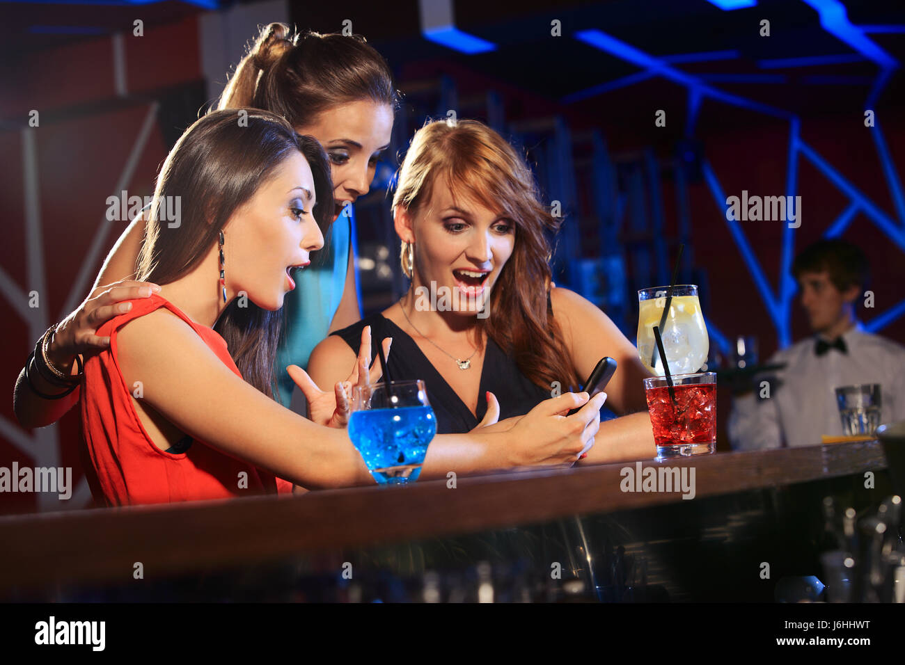 Three beautiful young women friends having fun looking at something ...