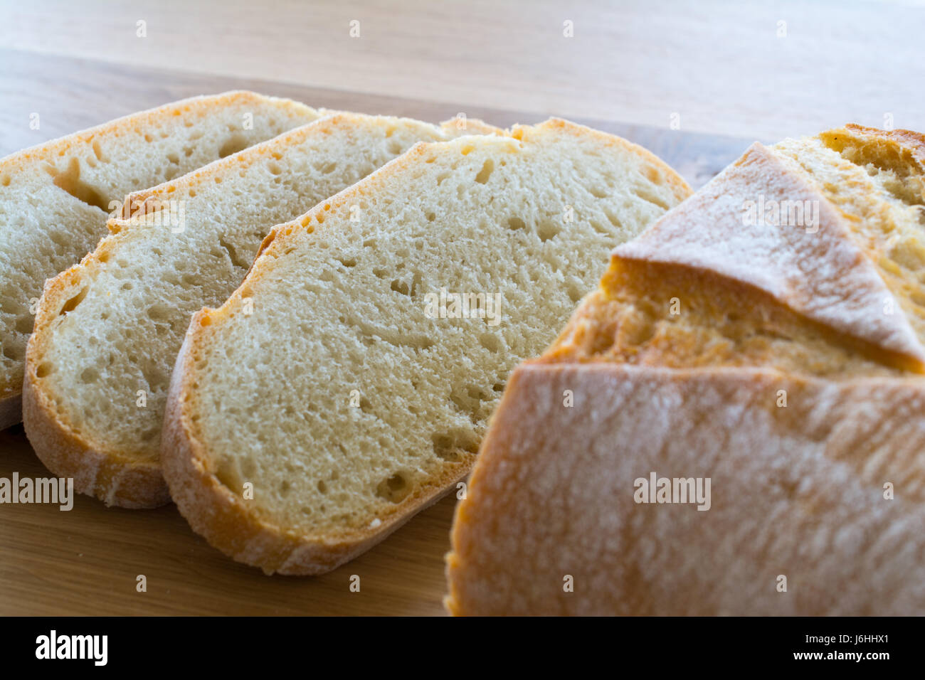 Slices and loaf of bread on wooden oak table top. Shallow depth of ...