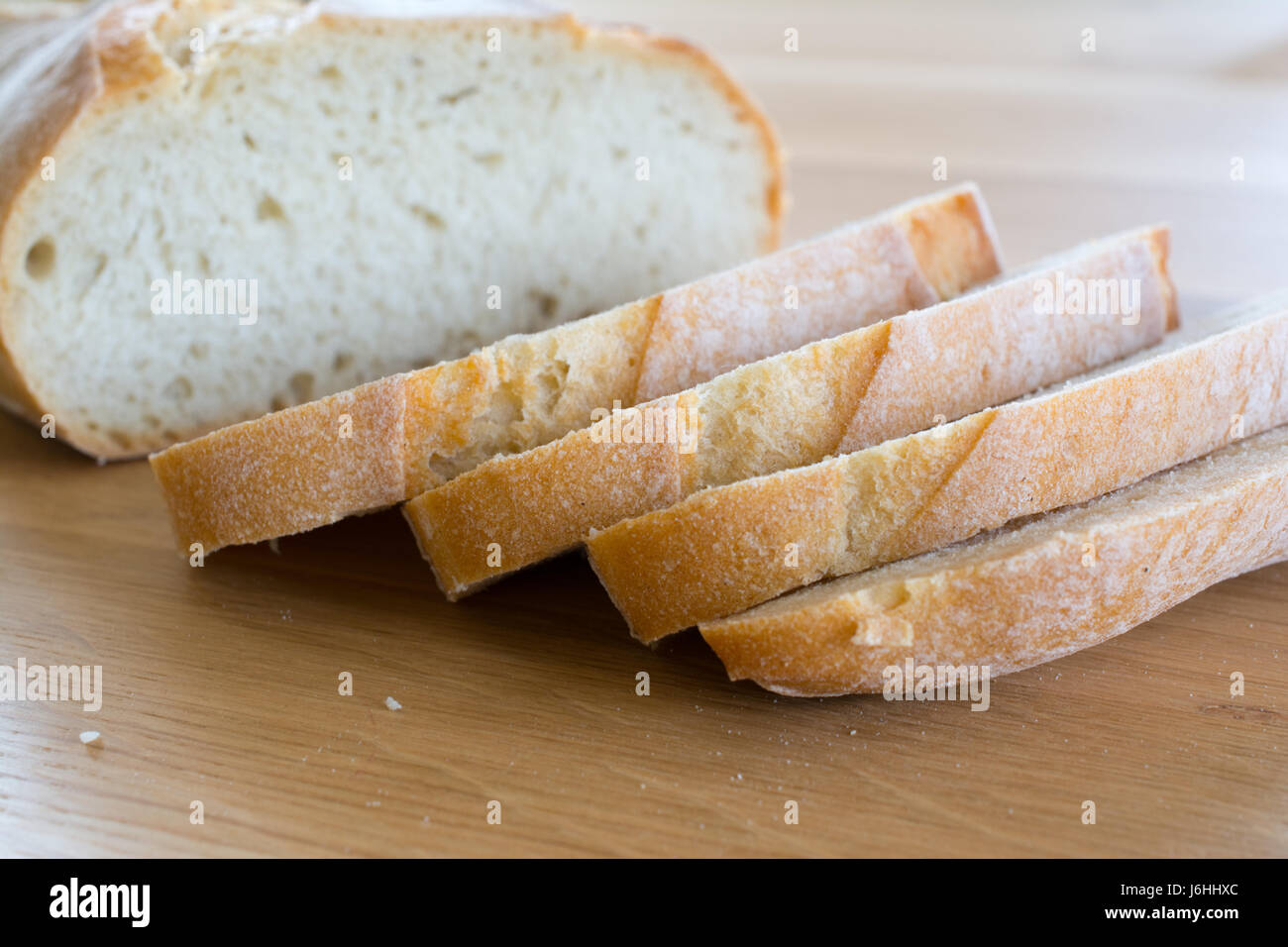 Slices and loaf of bread on wooden oak table top. Shallow depth of ...