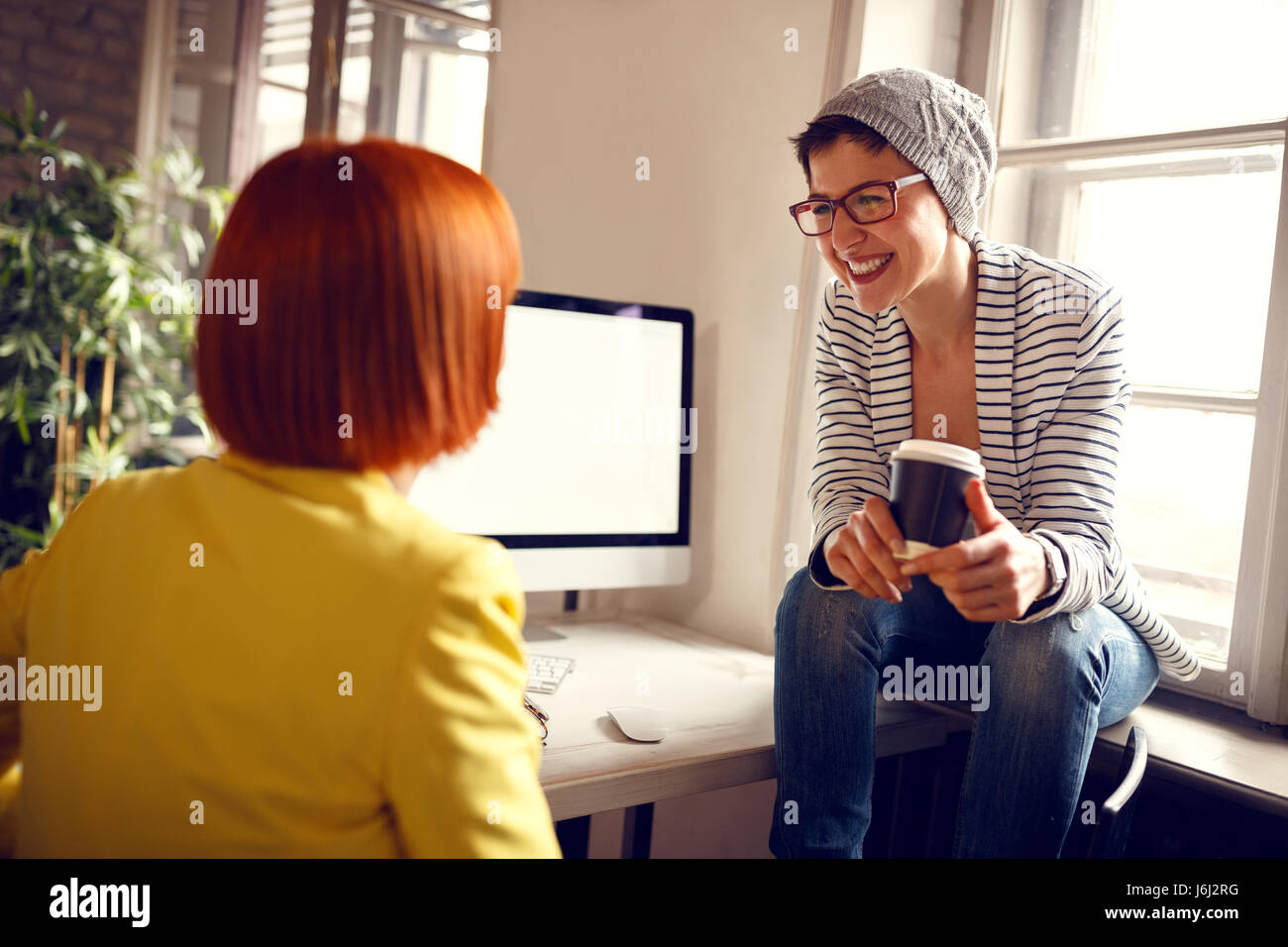 Two female colleagues chat on break in office Stock Photo - Alamy