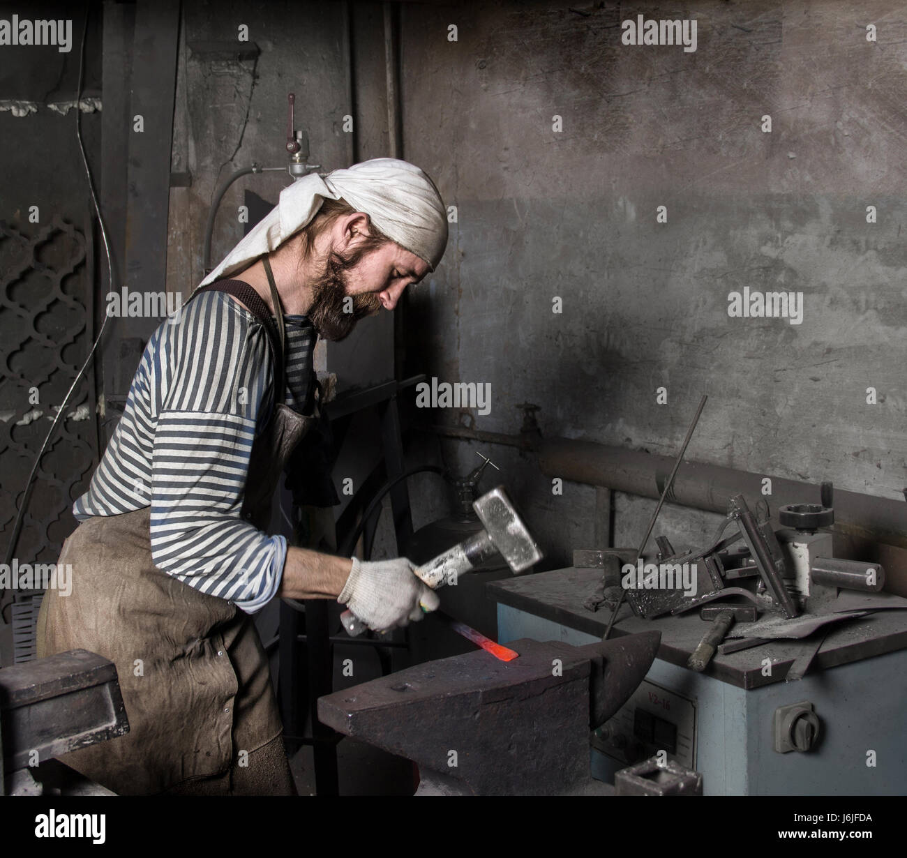 the senior blacksmith hammering a hot metal rod Stock Photo - Alamy