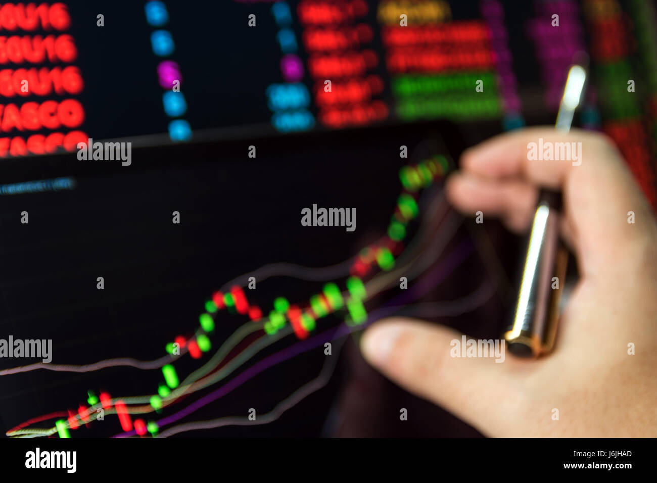Blur finger and pen point to tablet graph Stock market trading screen ...