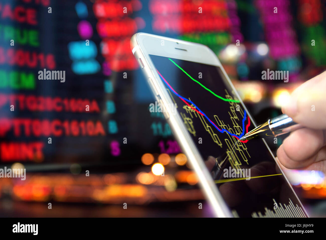 A businessman using a mobile phone to check graph stock market data on ...