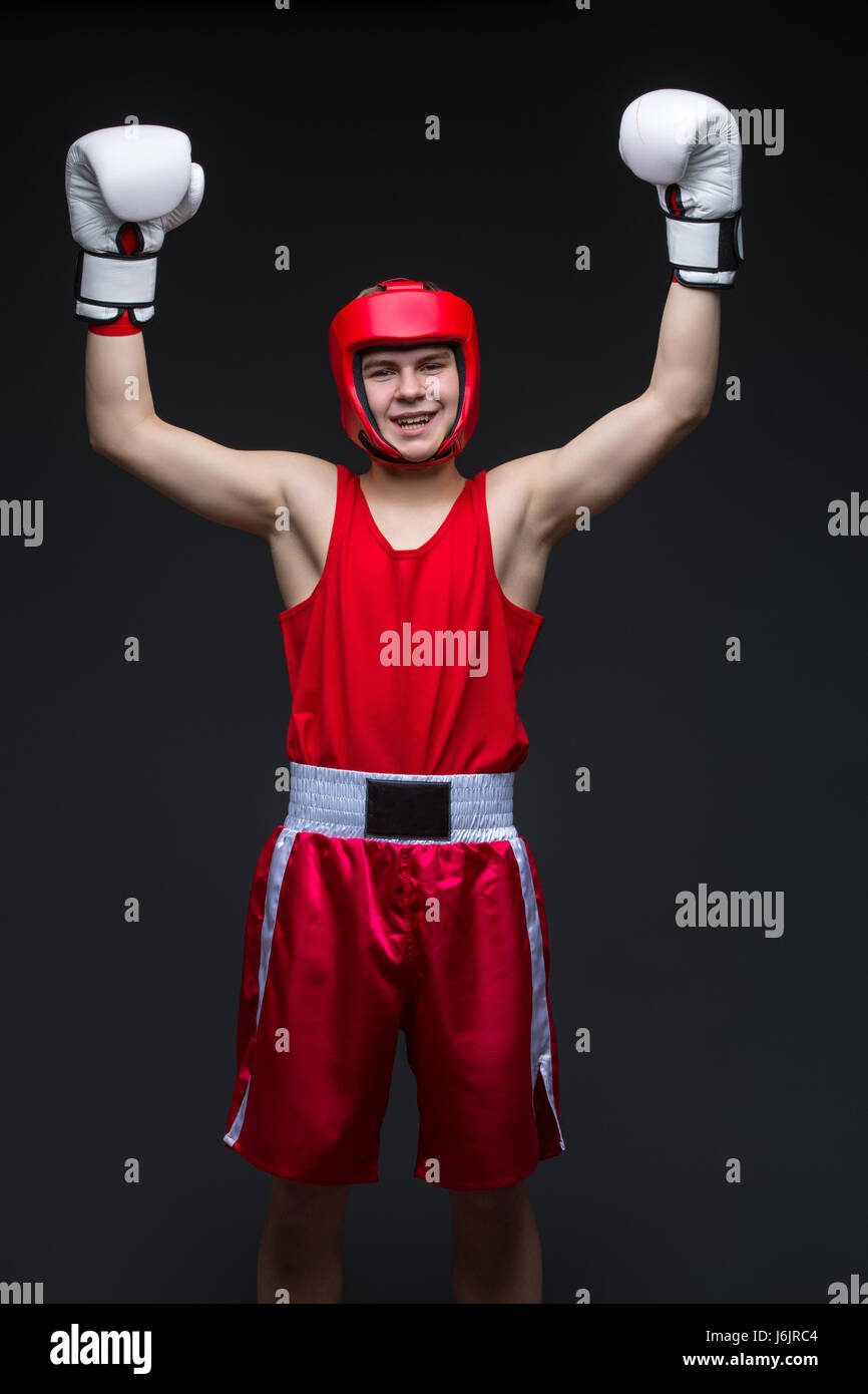 Teenage boxer in red form and white boxing gloves with hands up. Young ...