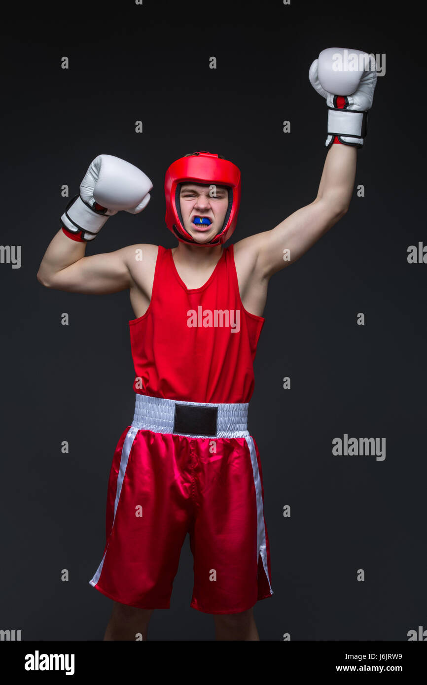 Teenage boxer in red form and white boxing gloves with hands up. Young ...