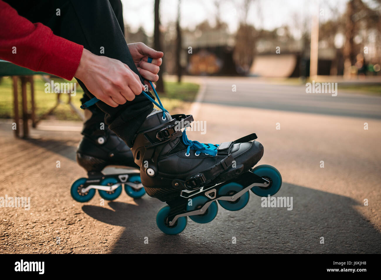 Roller skater sitting on the bench and lace up skates. Male ...