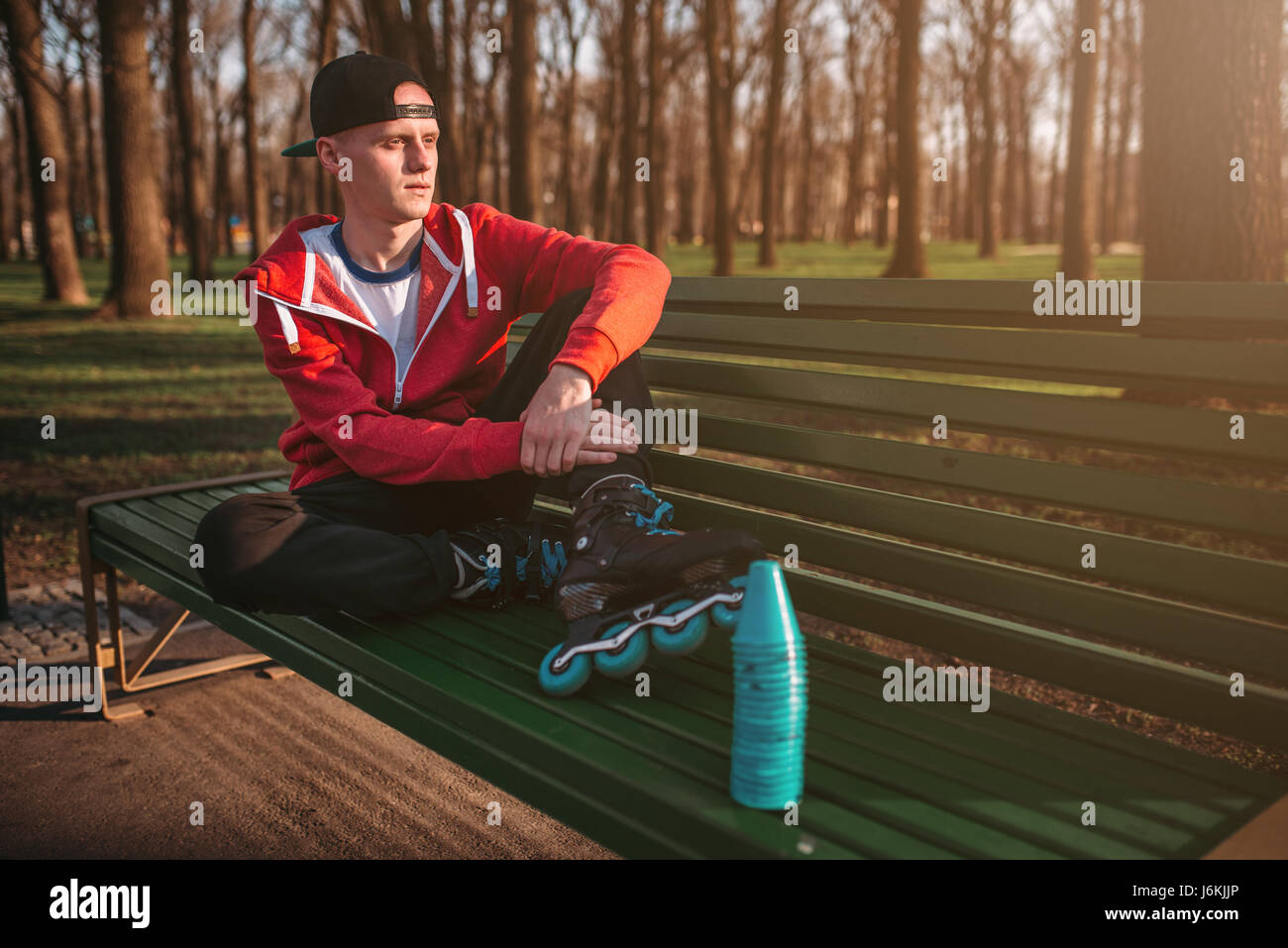 Roller skater posing on the bench in skates, city park on background ...