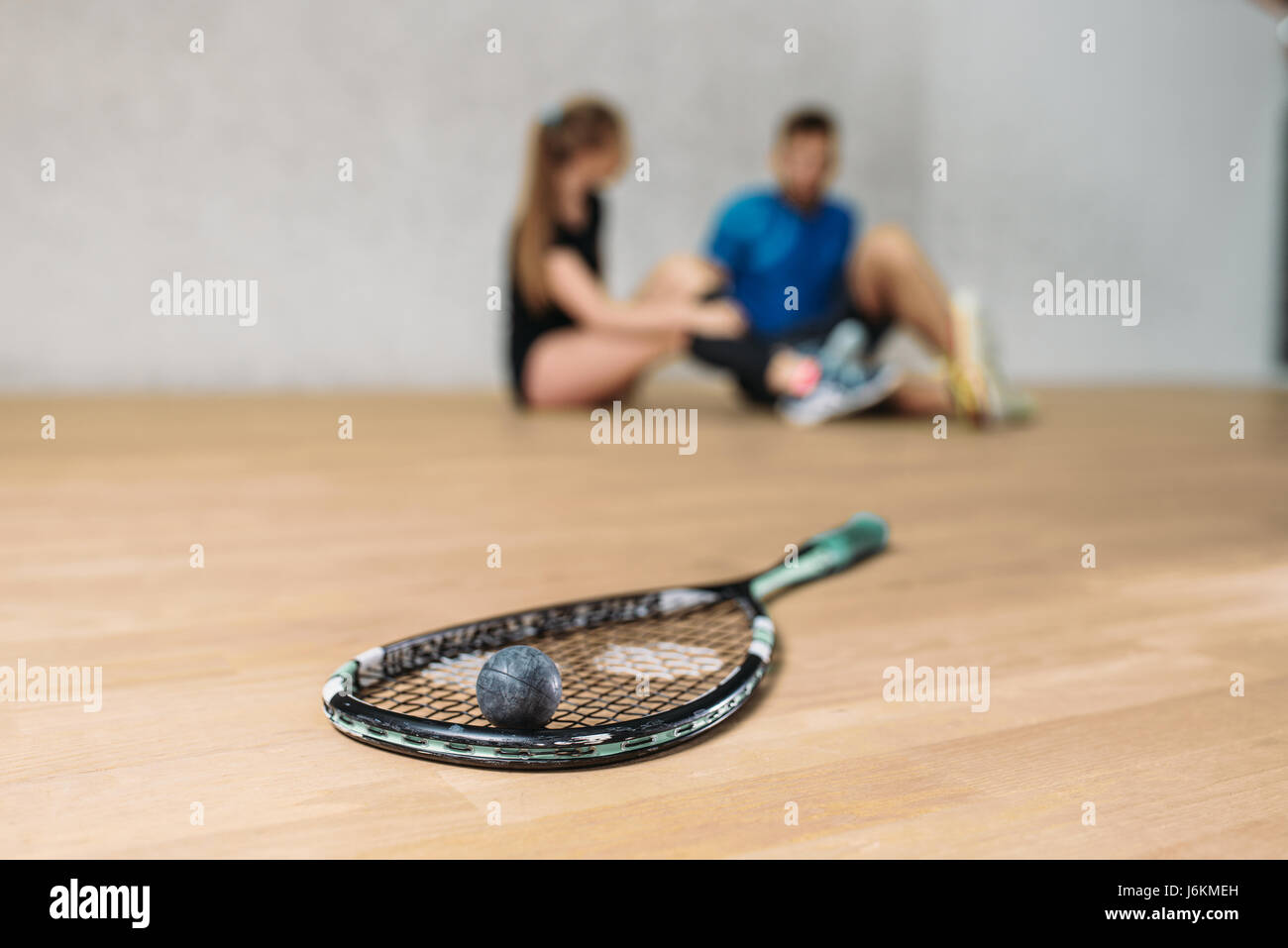 Squash game concept, racket with ball, young couple sitting on the ...