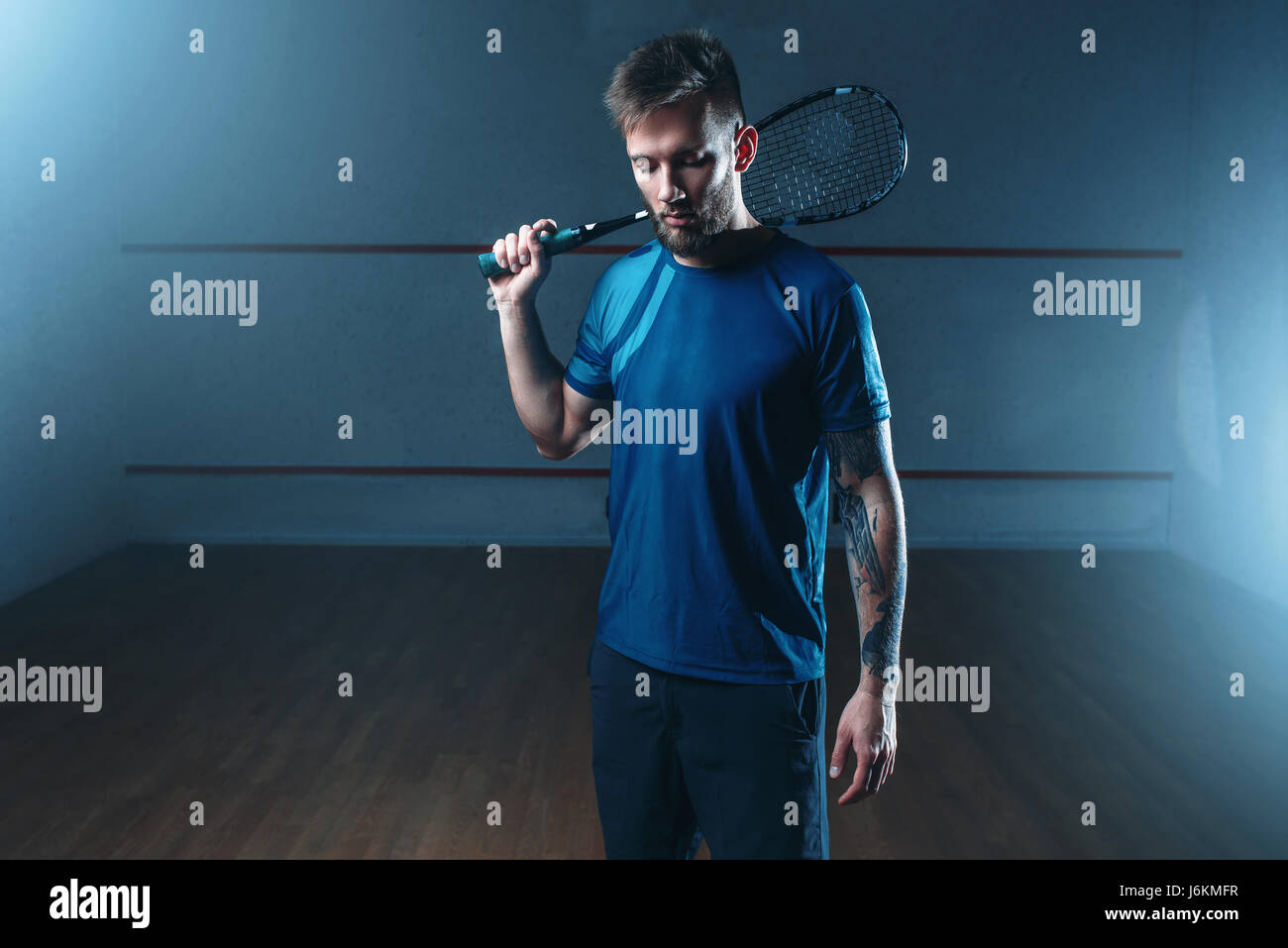 Male squash player with racket, indoor training court on background ...