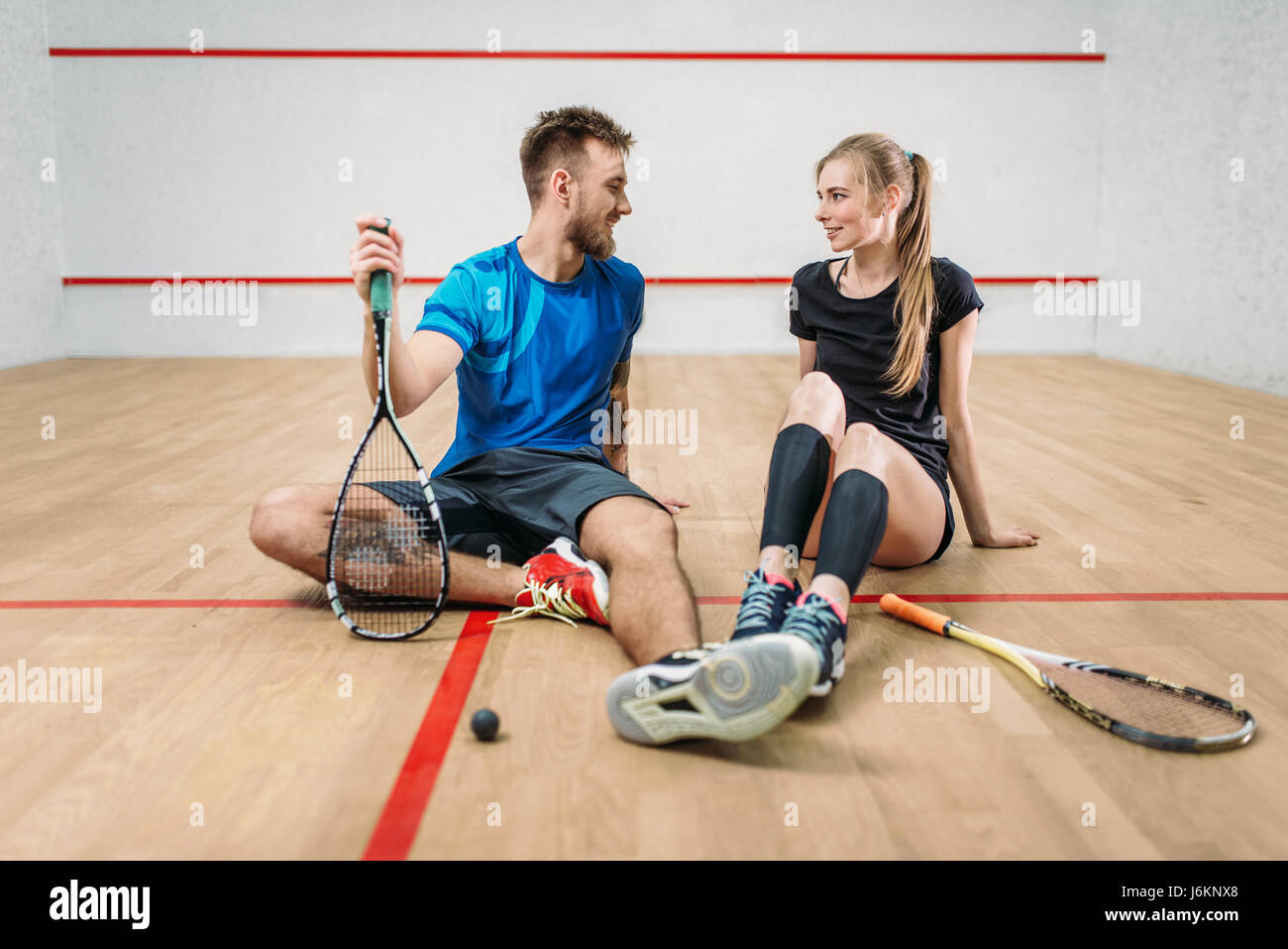 Squash game concept, rackets with ball, young couple sitting on the ...
