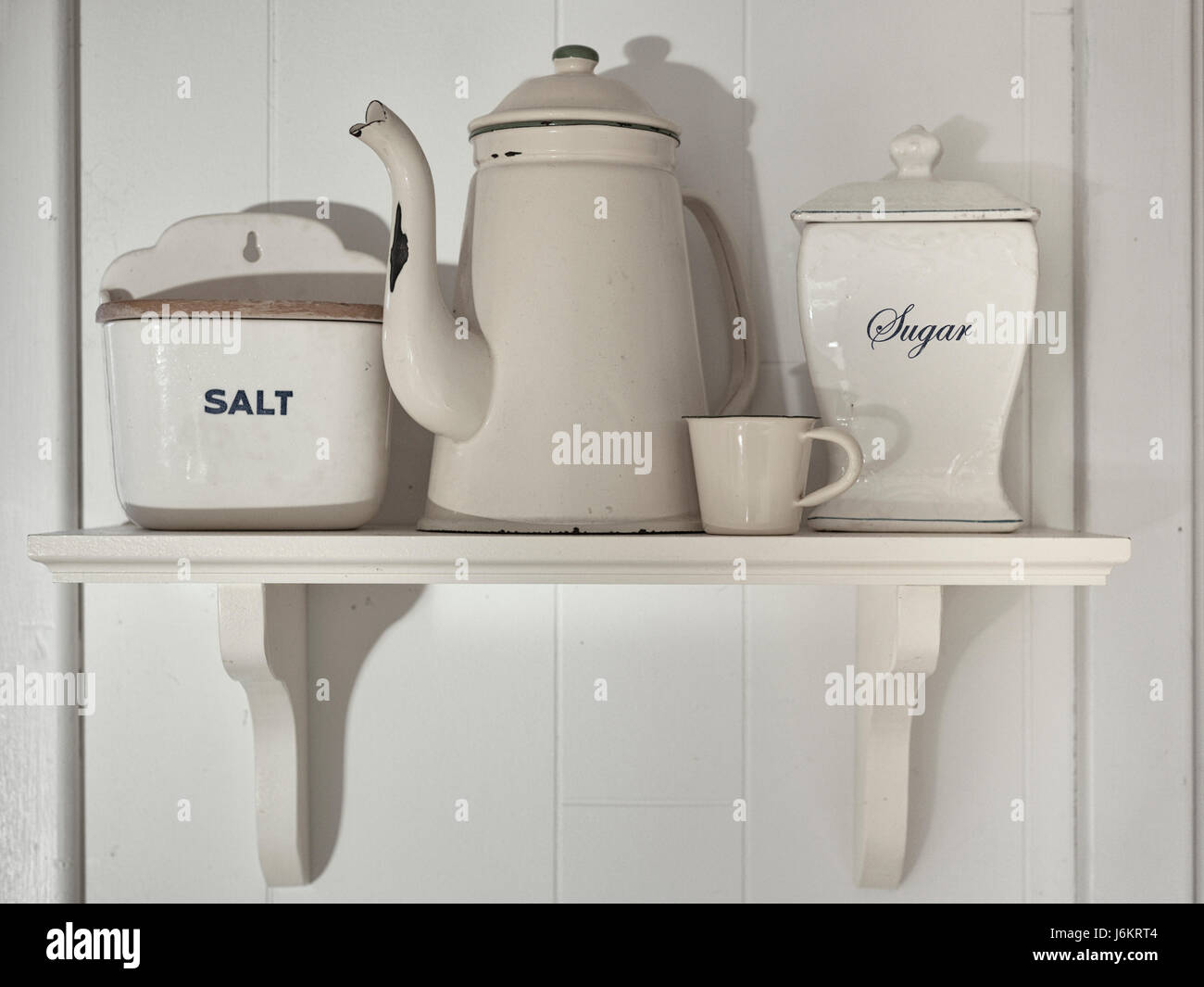 Old tea kettle and cup, sugar and salt containers on a shelf at the ...