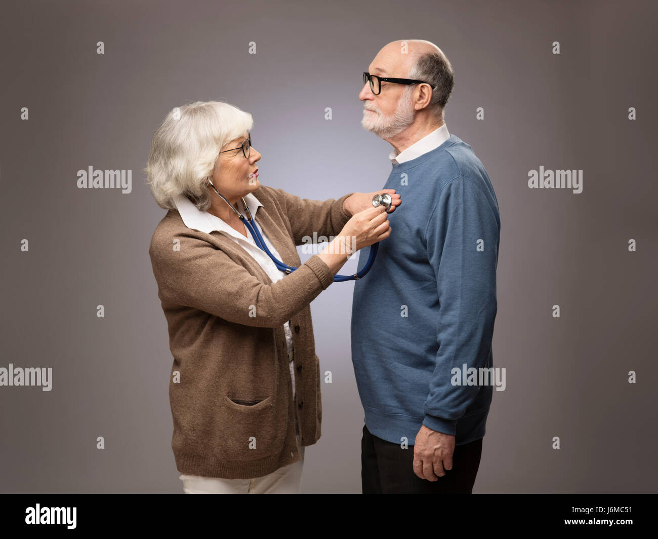 Old couple. Senior woman taking care, checking heart beat of husband ...