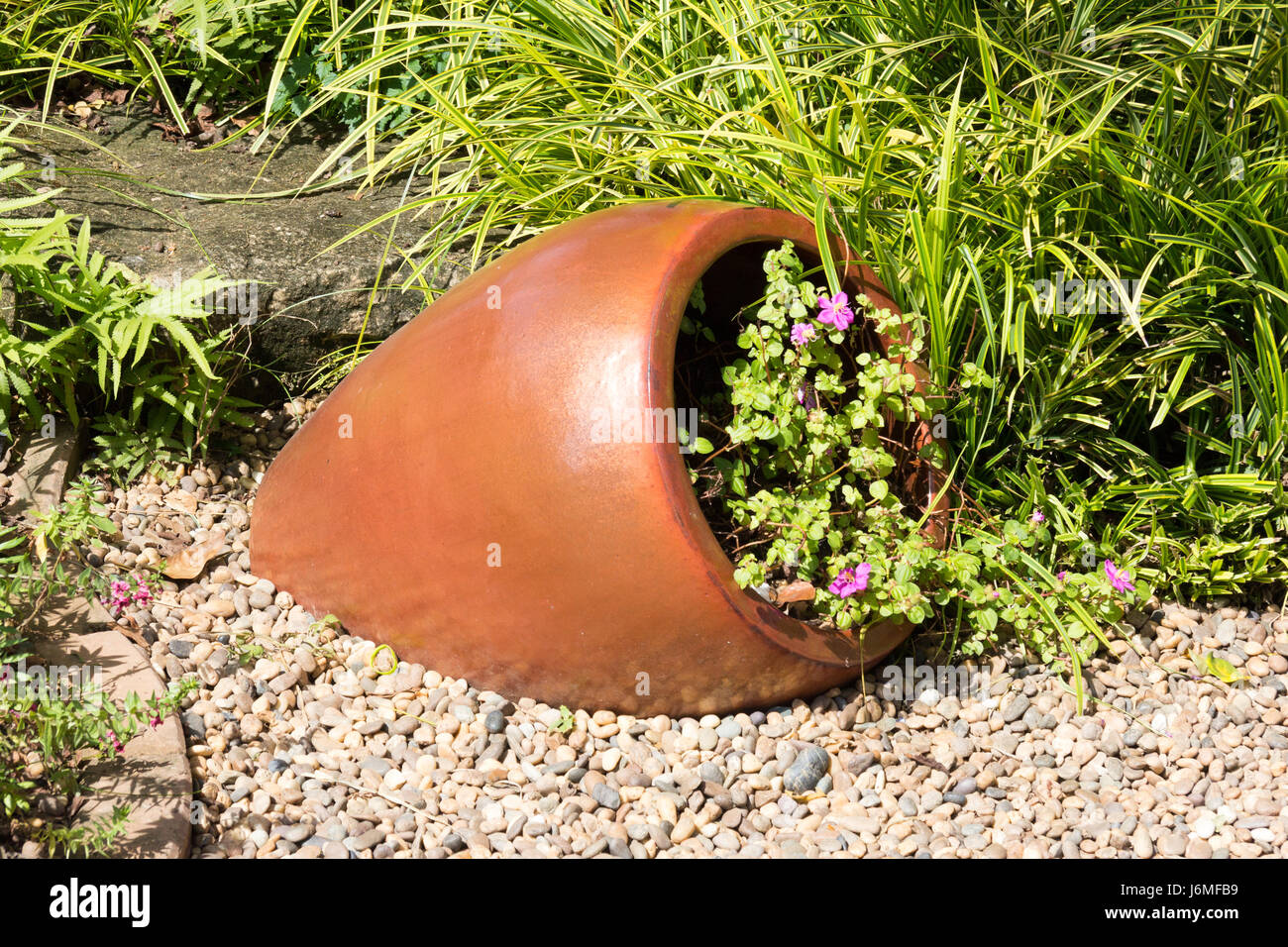 Plantpot embedded in small stones in garden Stock Photo - Alamy