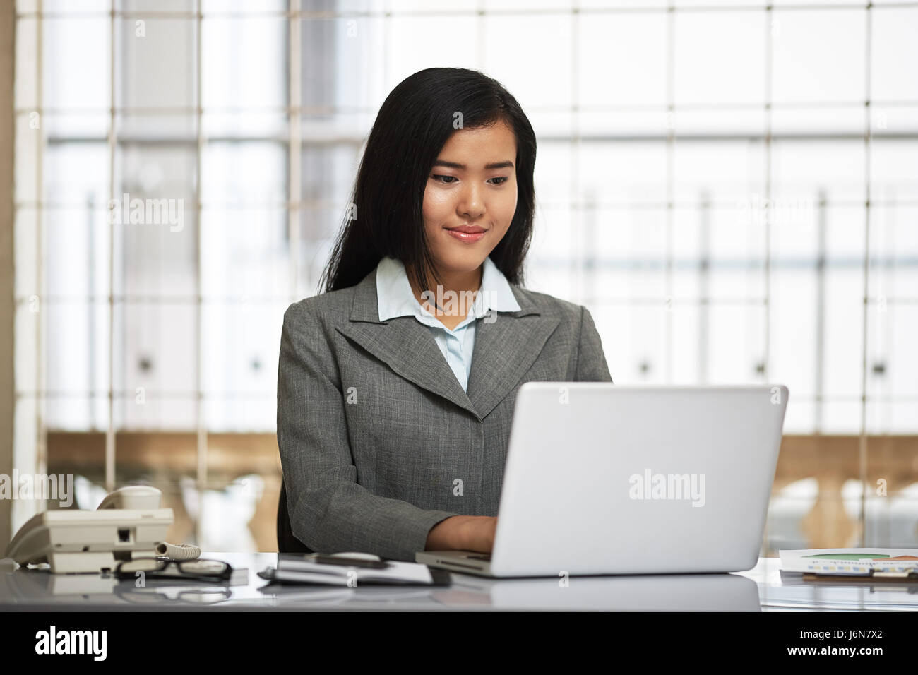 friendly smile of front desk businesswoman typing on her computer Stock ...